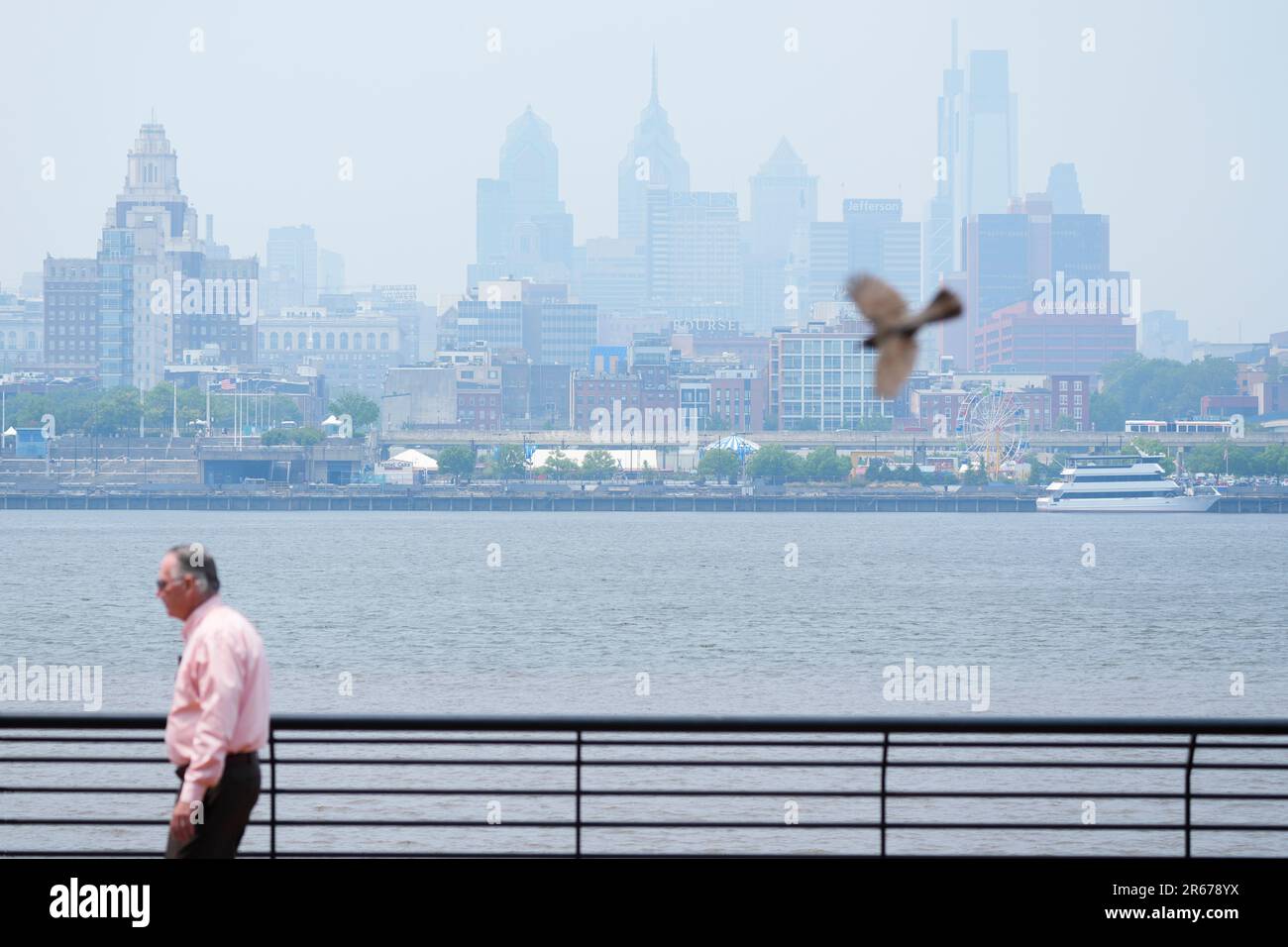 A person walks in Camden, N.J., in view of the hazy Philadelphia ...