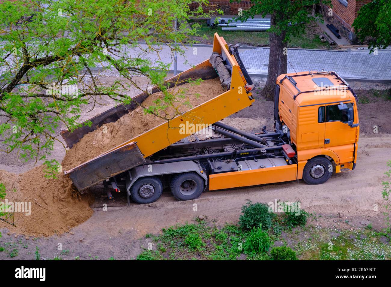 A large orange dump truck unloads the sand Stock Photo - Alamy