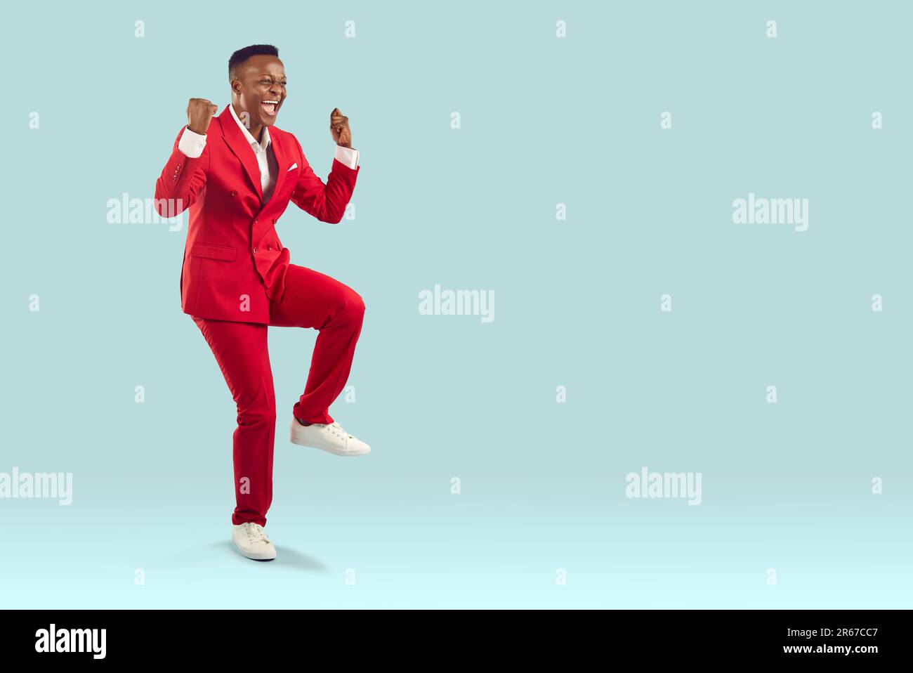 Happy excited Afro American man in red suit celebrating victory on copy ...