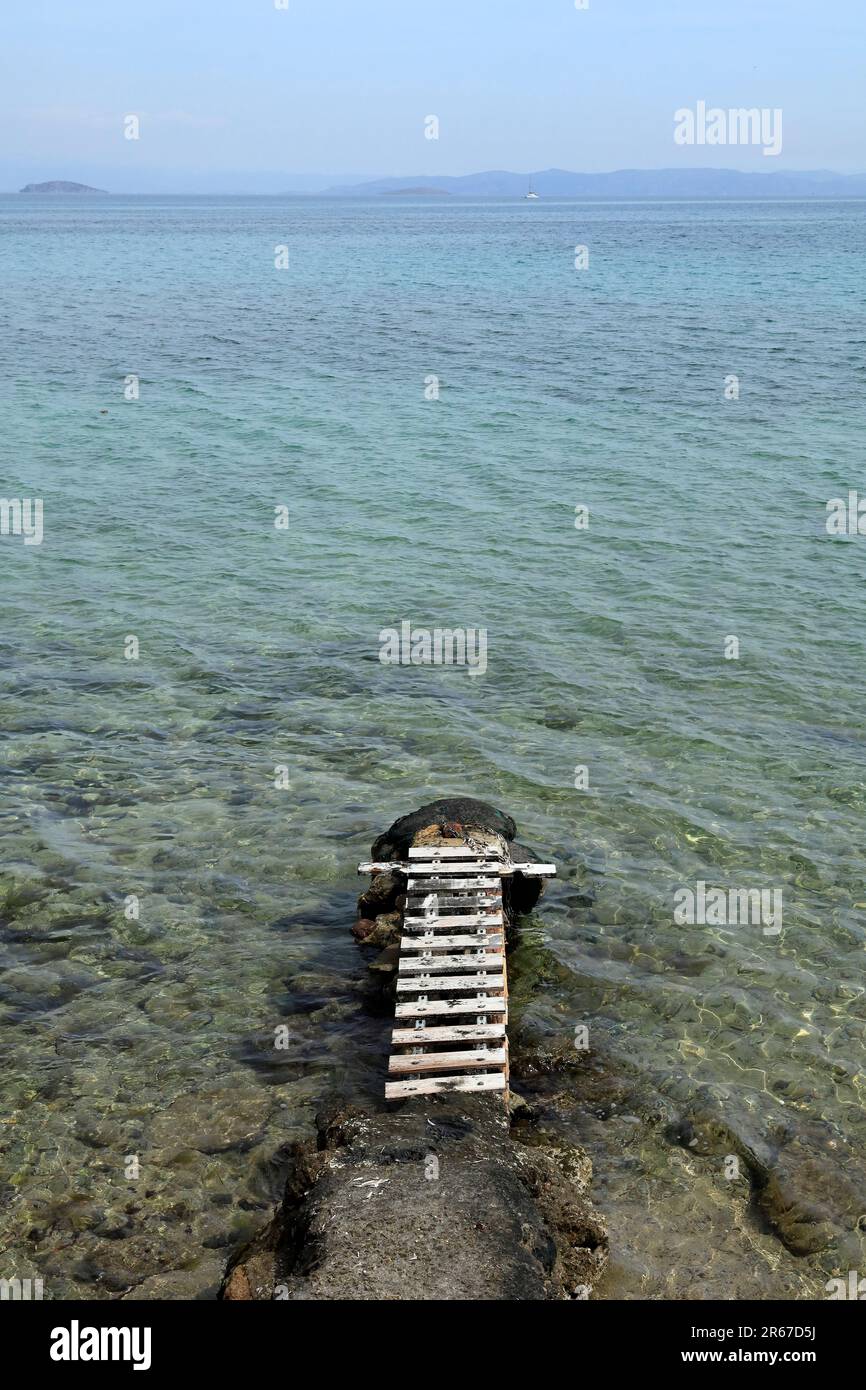 Small old wooden jetty leading the eye to the horizon, Agistri island ...