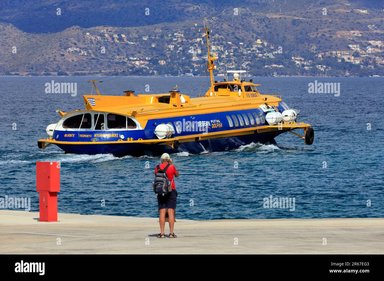 Photographer on the harbourside at Skala,Agistri photographing the Aegean Flying Dolphin ferry ...