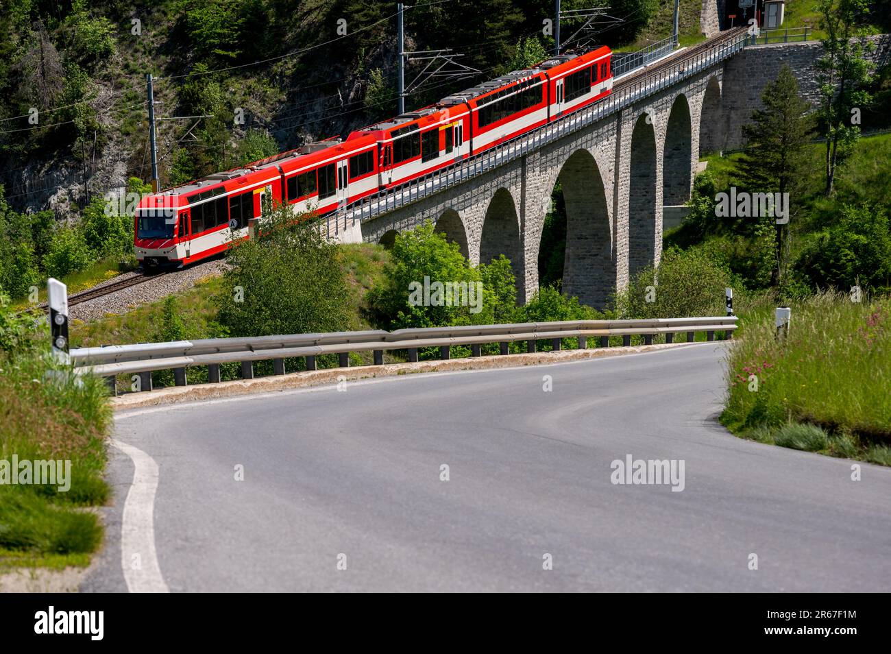 One red train passing on the circular viaduct bridge in spring ...