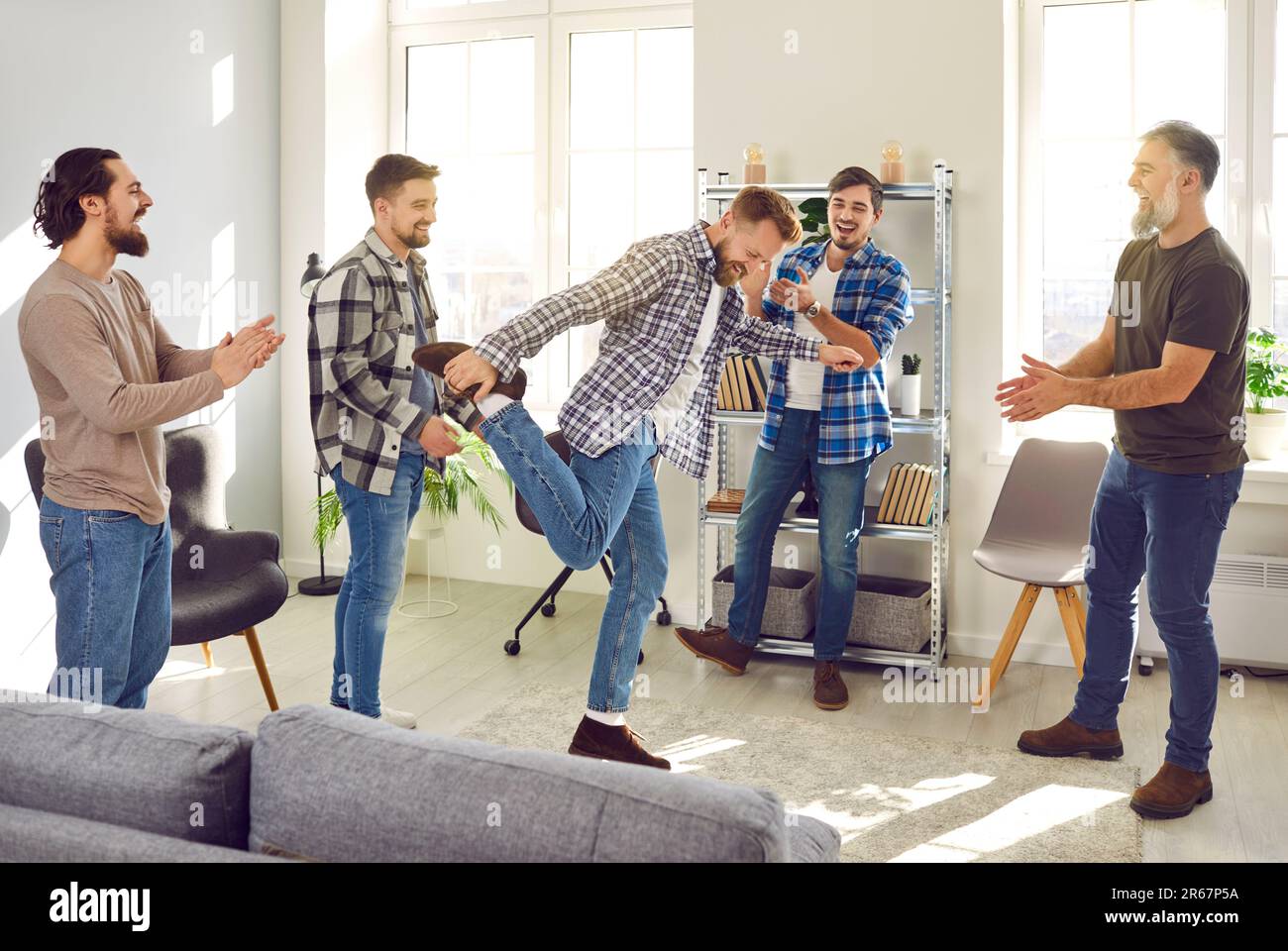 Happy man dancing while his cheerful friends are standing around and ...
