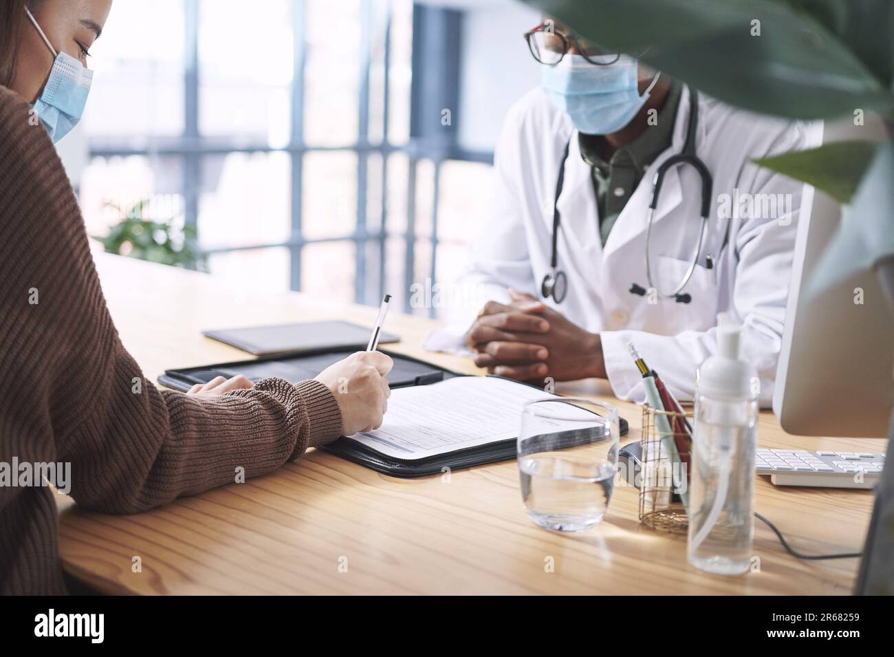 Please sign the indemnity form. a young doctor sitting with his patient ...