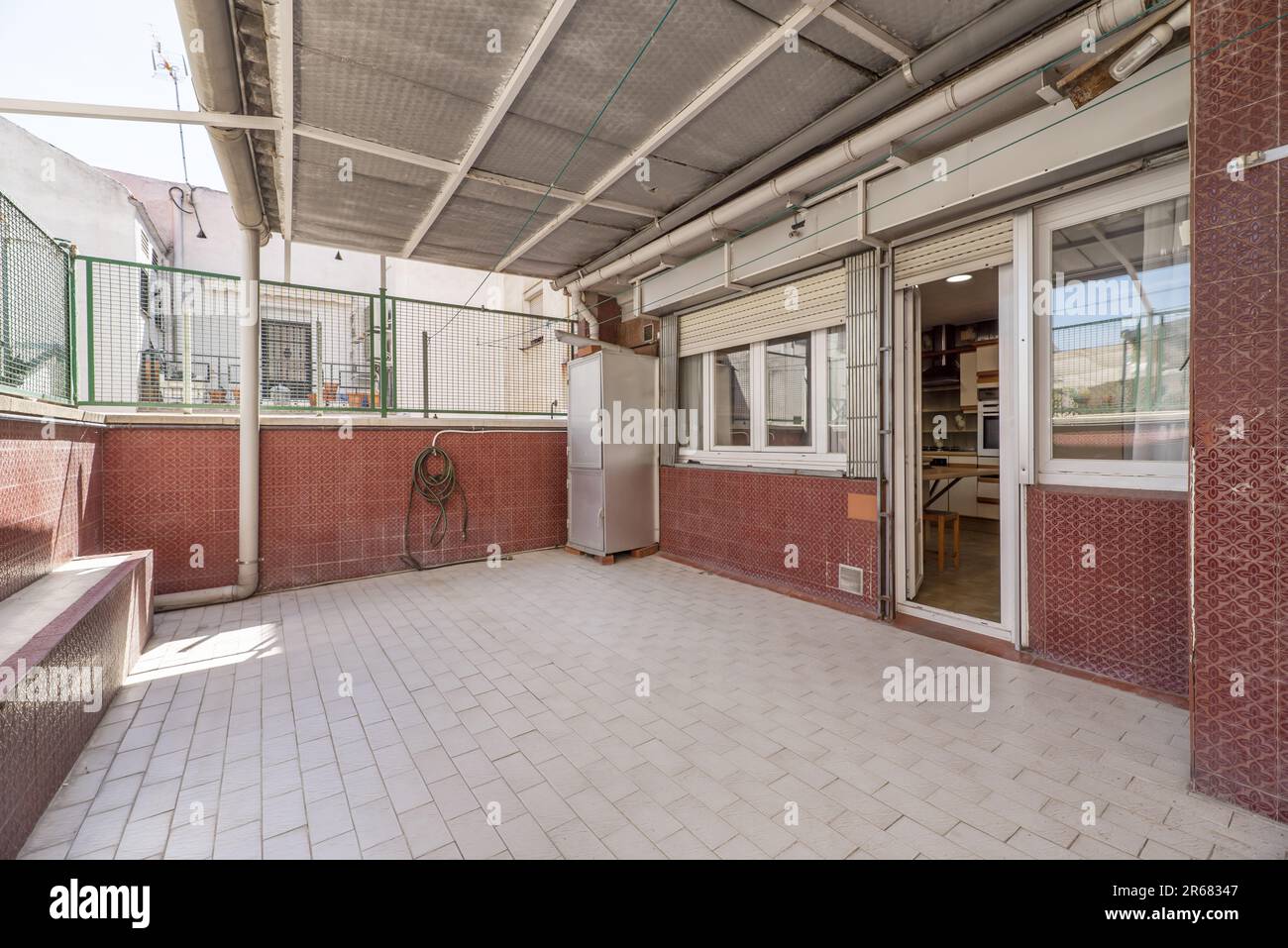 Courtyard of a house with a white tile floor and red tiles on the walls ...
