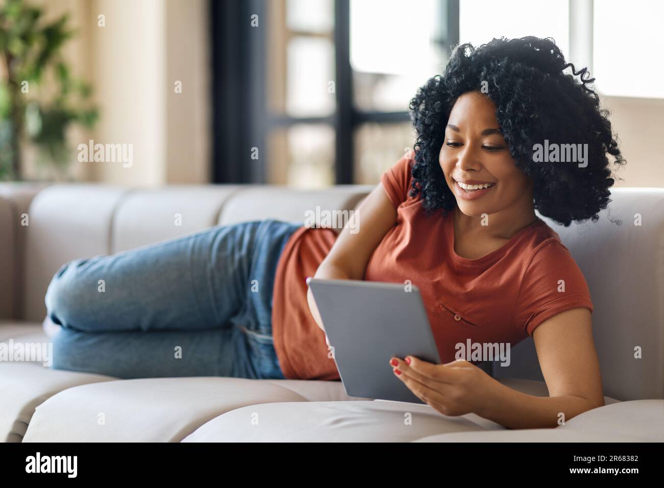Woman lying on couch tablet hi-res stock photography and images - Alamy