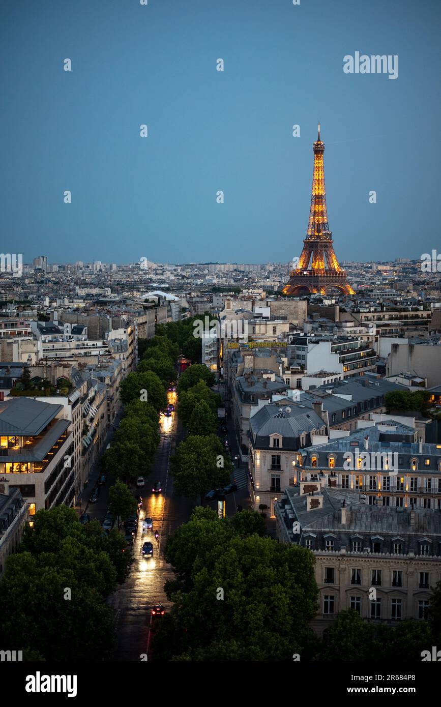 A vertical aerial view of the glowing Eiffel Tower over the skyline of ...