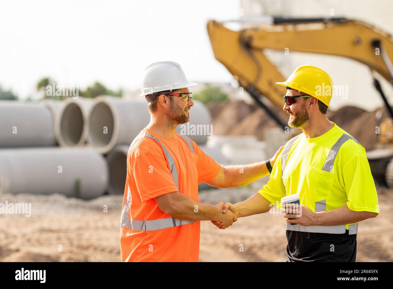 Two construction workers with hardhat helmet on construction site ...