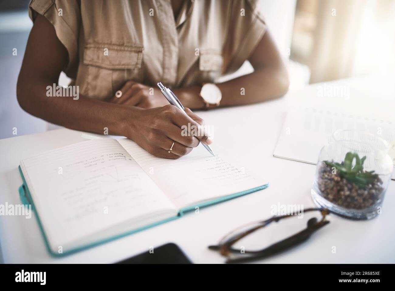 Organization is the hallmark of success. a young businesswoman writing ...