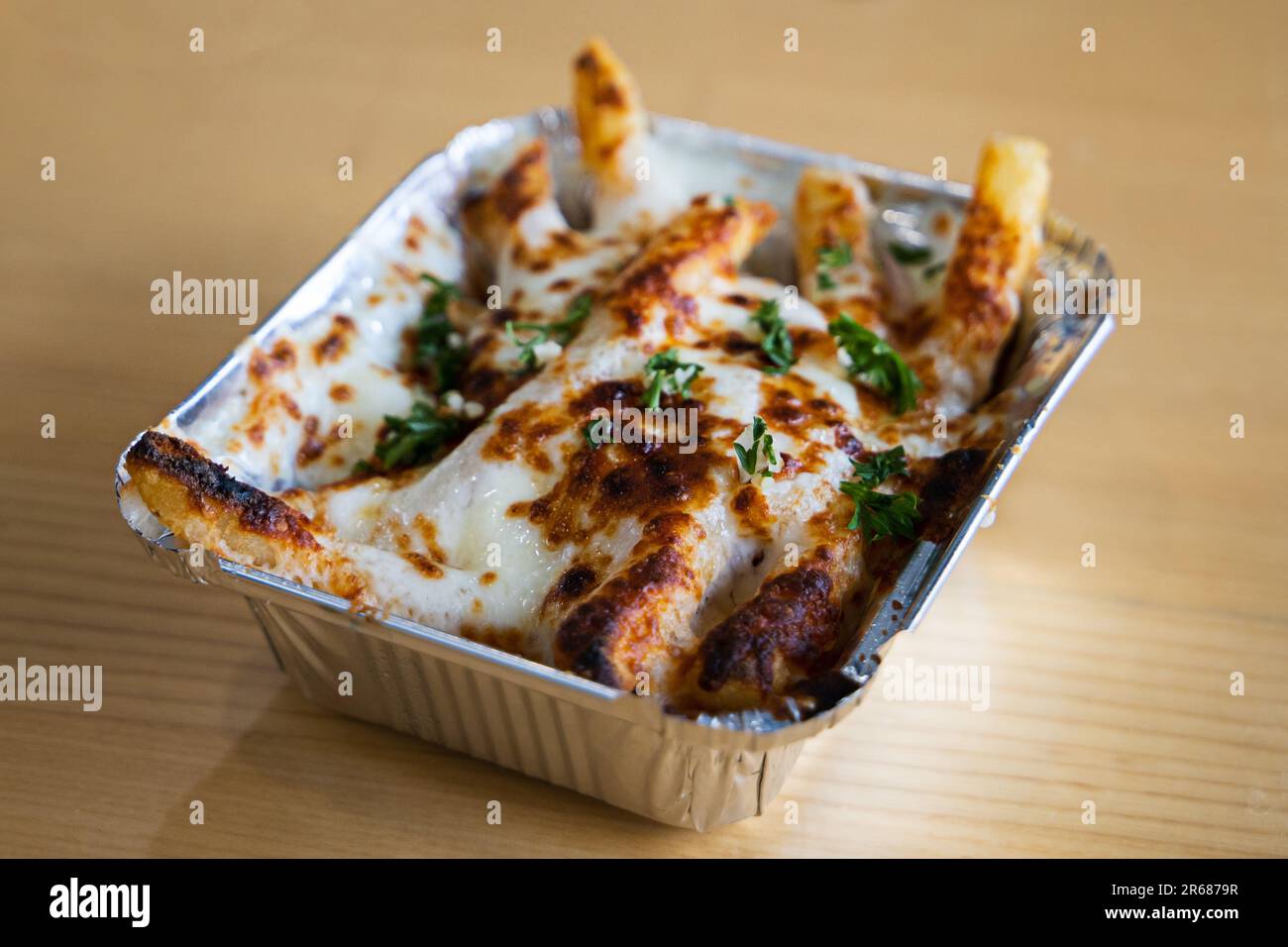 a metal take out container with baked Greek french fries loaded with ...