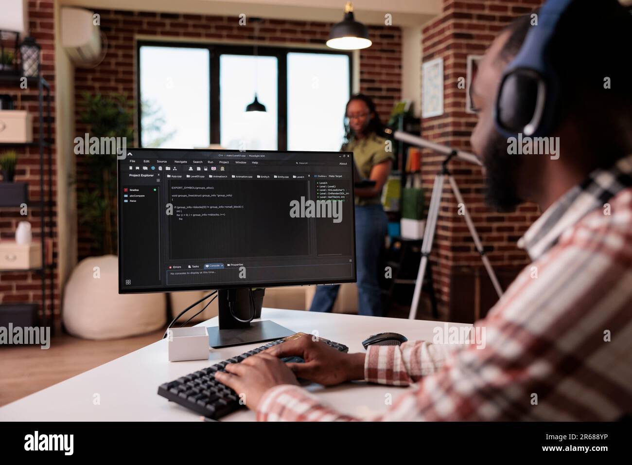 African american man with wireless headphones writing code on personal computer while girlfriend ...