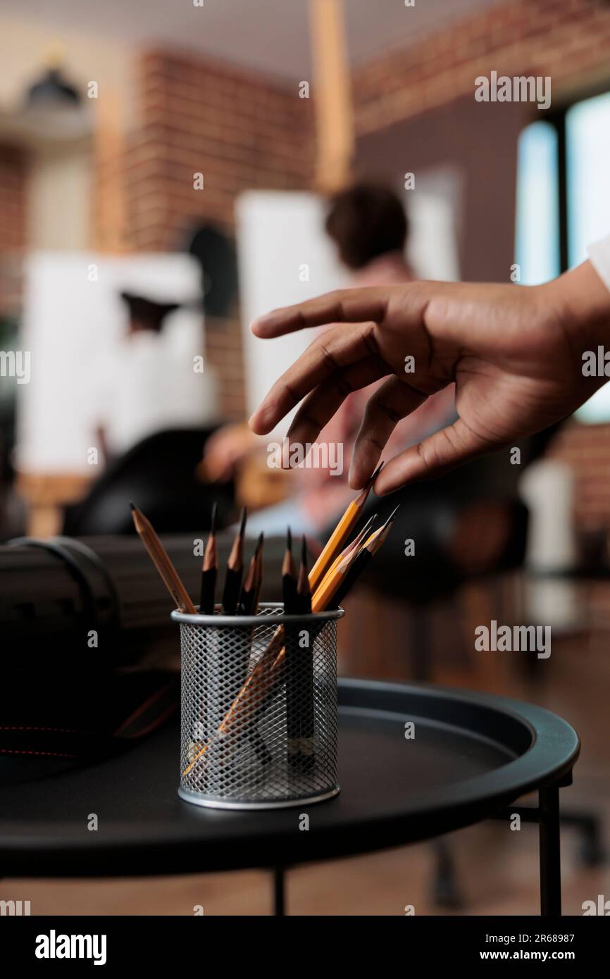 Close up of male hand taking pencil out of metal cup holder during ...