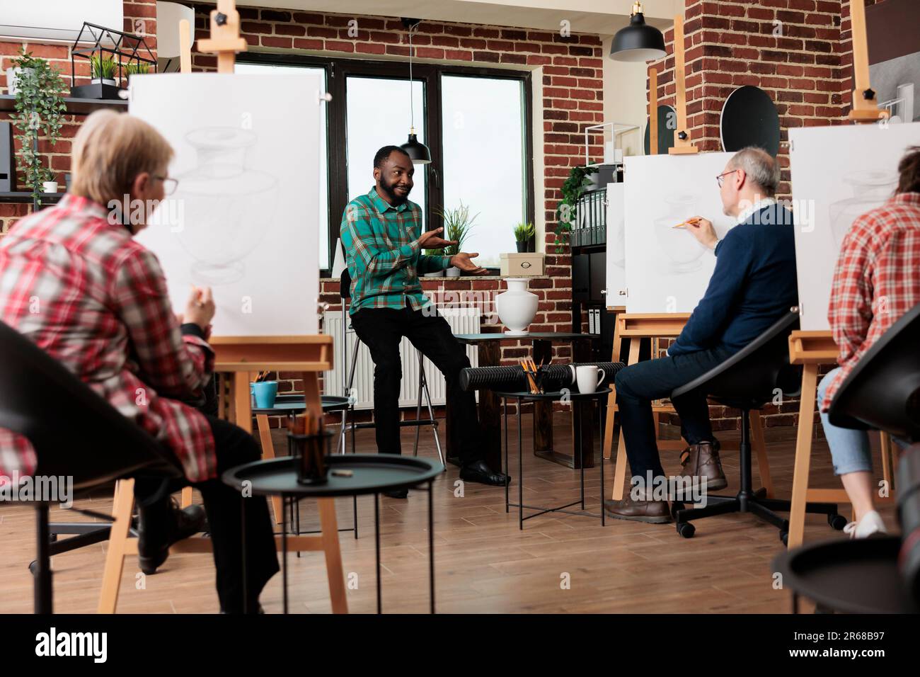 Friendly African American man teacher guiding group of different aged ...