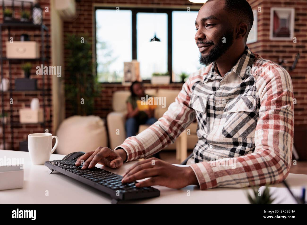 Smiling african american freelancer working remote typing and looking ...