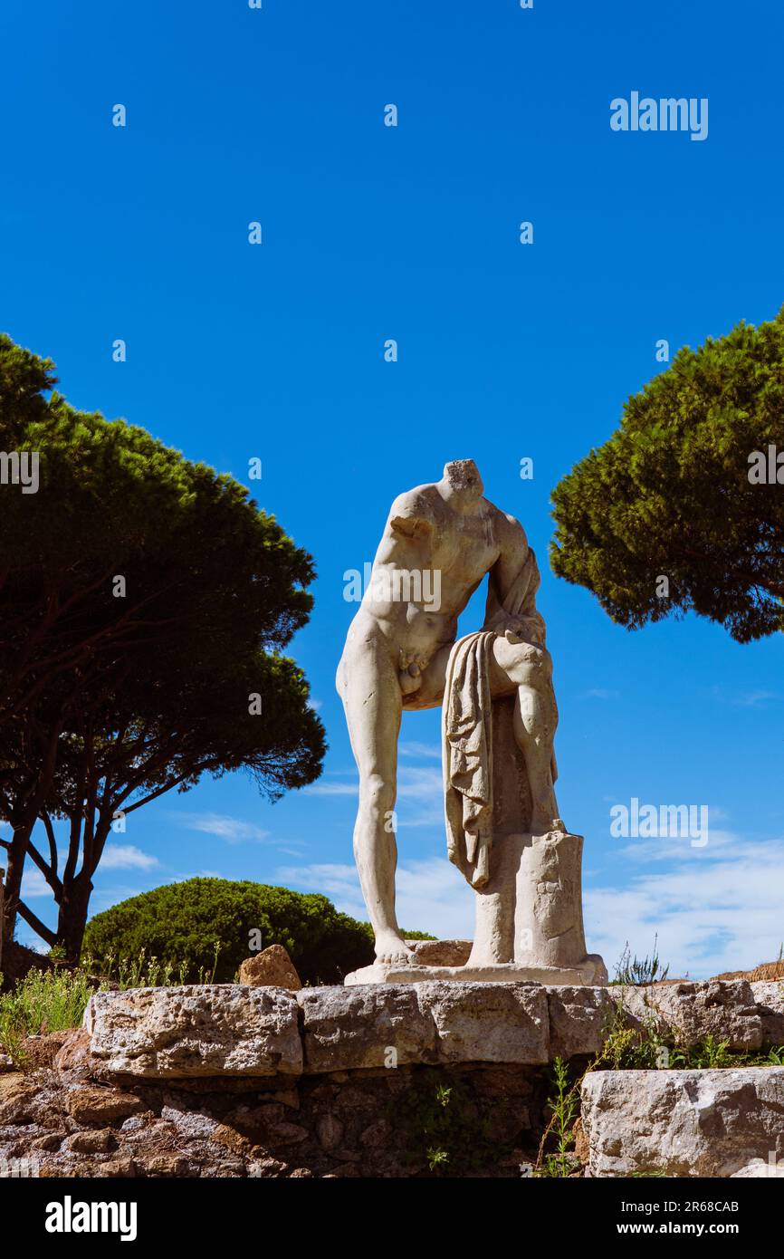 A stone statue of a human figure in a scenic park surrounded by lush ...