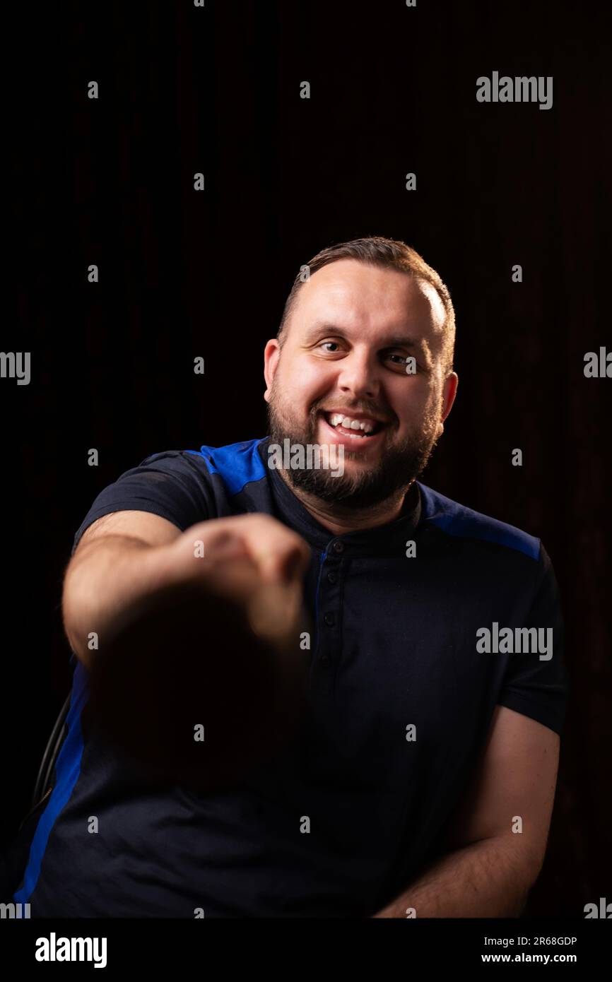 A young strong positive man holds a bat in his hand pointing at the ...