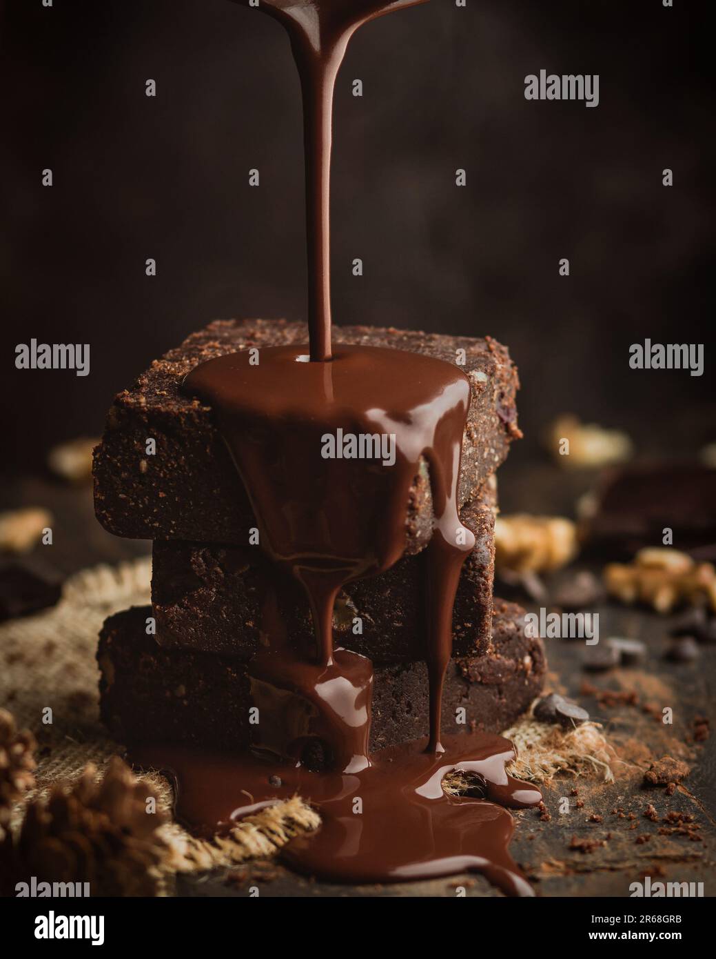 A vertical closeup shot of chocolate dripping onto a stack of brownies ...