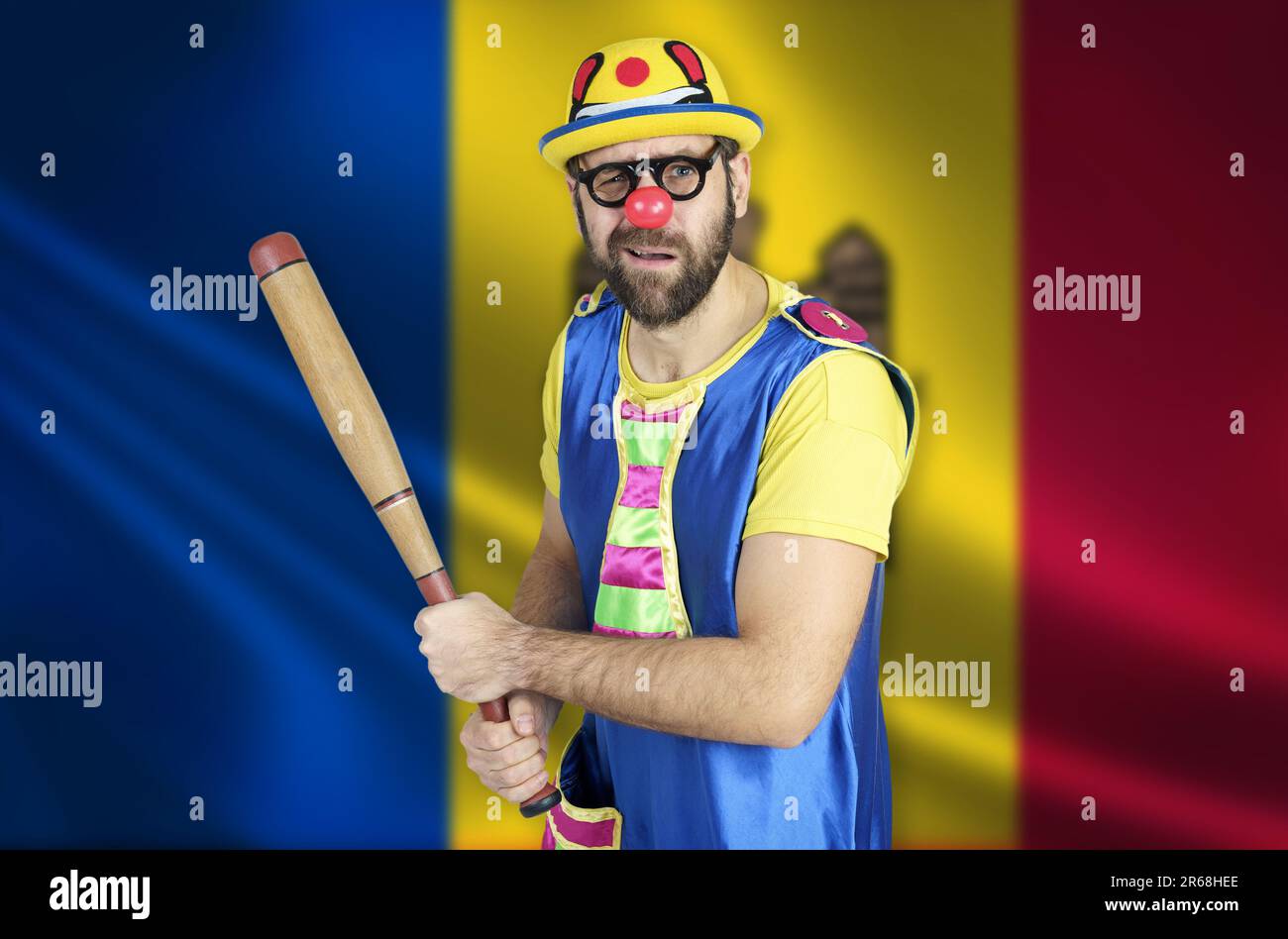 An insecure clown holds a bat in his hands against the background of ...