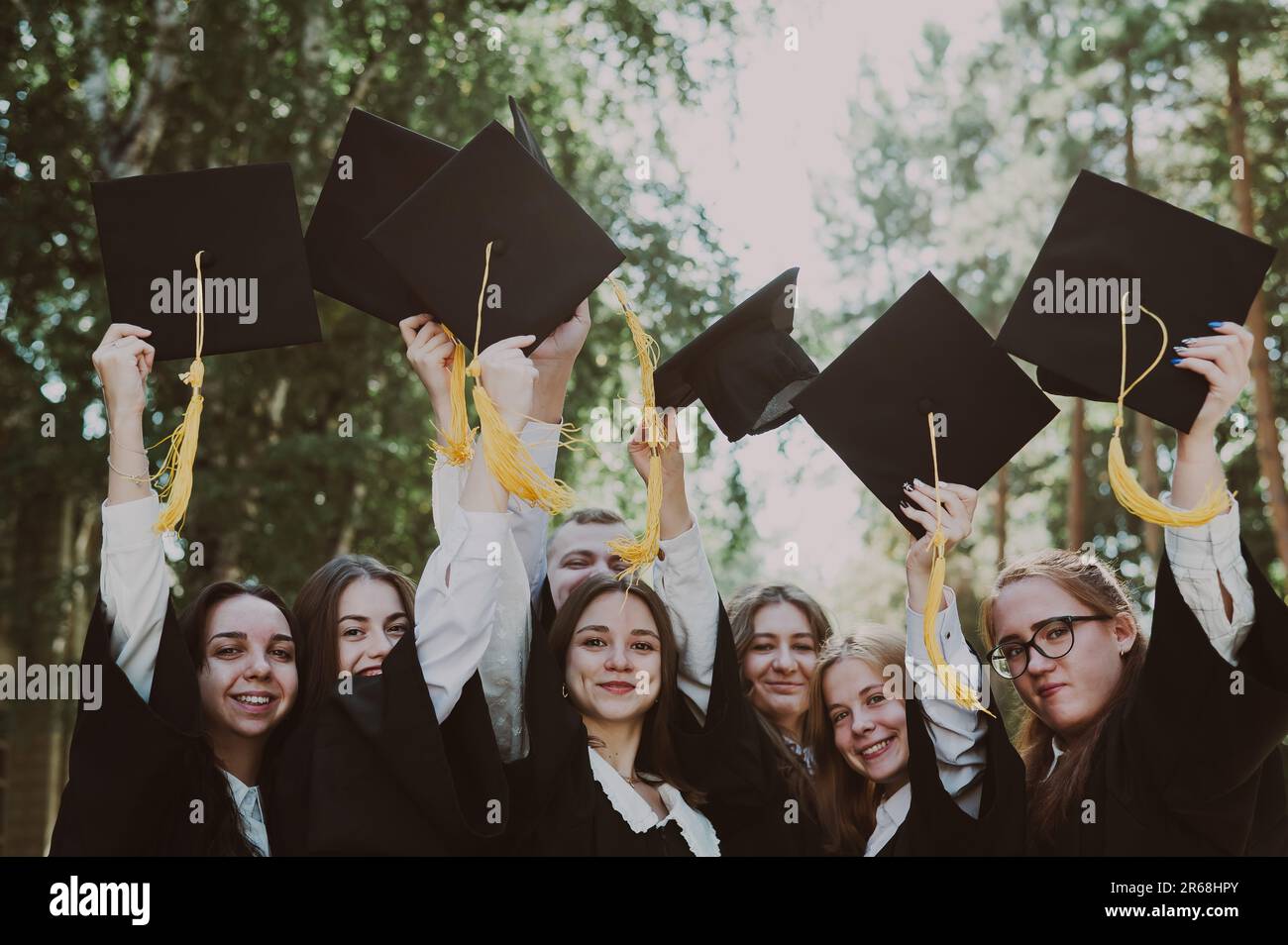 Classmates in graduation gowns throwing hats outdoors Stock Photo - Alamy