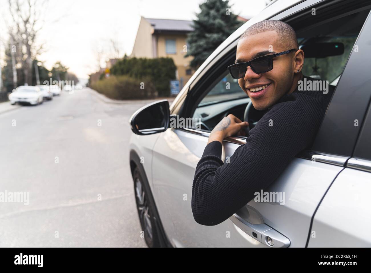 Afro-American man looks from the luxury car window and smiles while ...