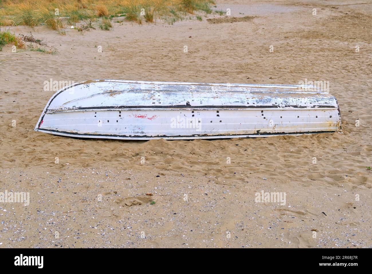 a small white boat capsized on the beach or in the desert Stock Photo ...