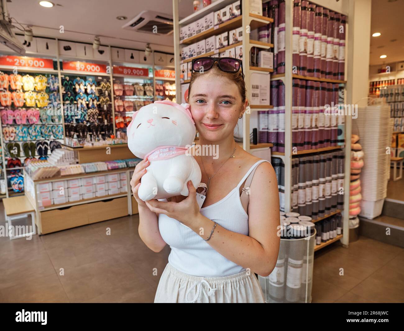 An attractive young female looking at a cute plush toy in the Miniso ...