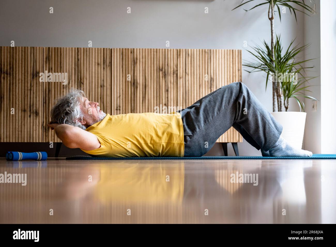 Senior man in yellow shirt working out practicing a pilates exercise ...