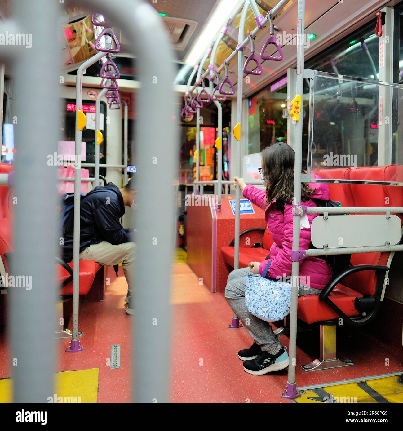 Interior of a public transportation bus in Taipei, Taiwan with two seated passengers; two riders ...