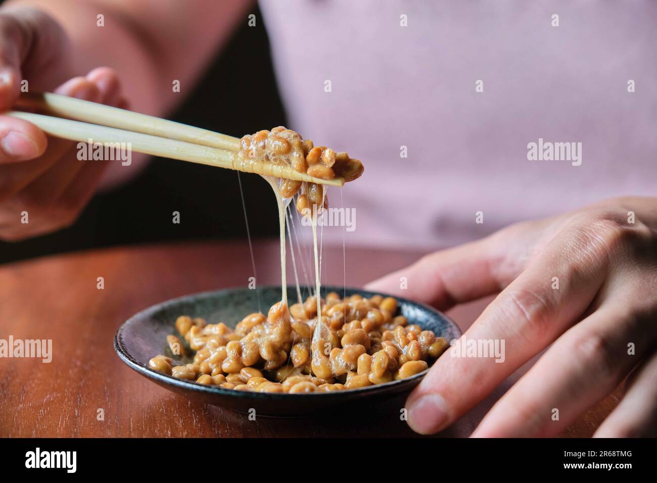 Unrecognizable man eating natto fermented soy beans with chopsticks ...