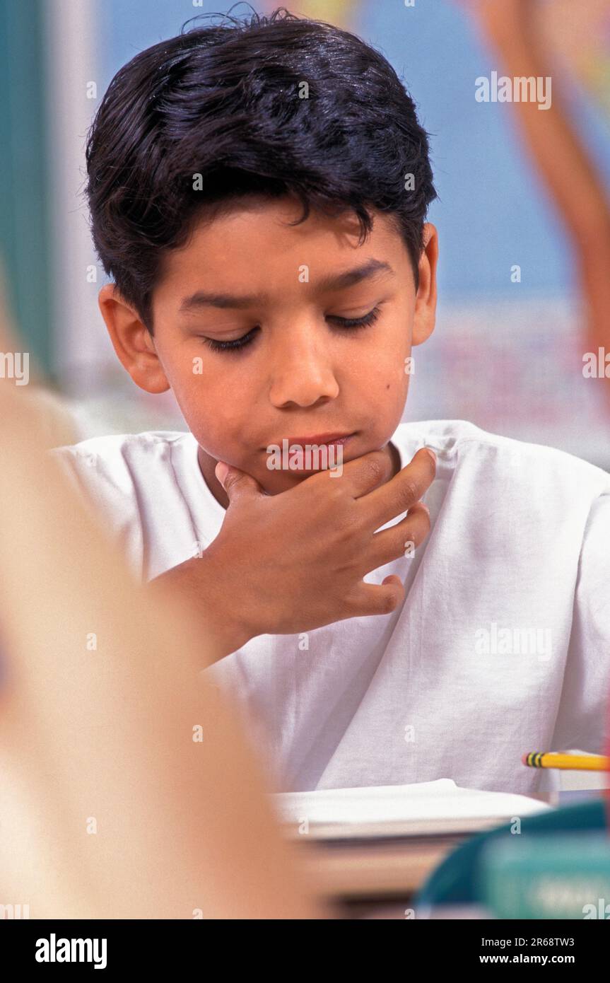 Latino elementary school student concentrating on schoolwork at his ...