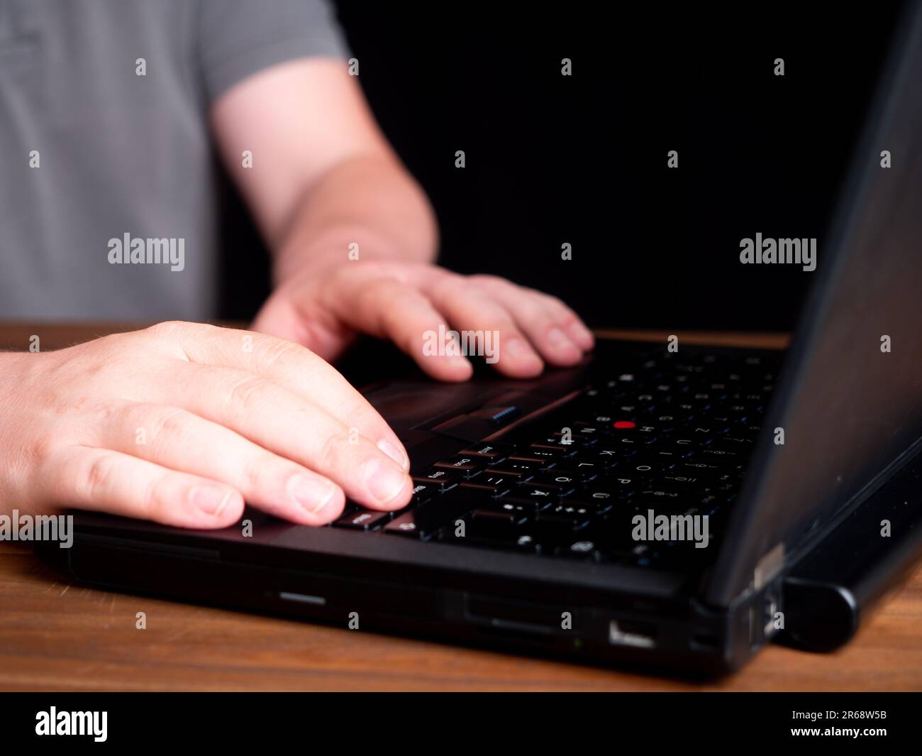 Dark and moody shot of a man working on laptop. Close up of mobile ...