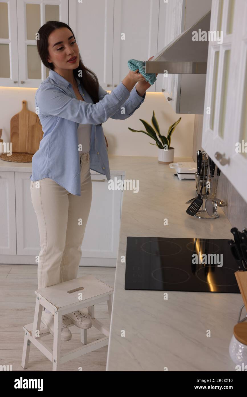 Woman on ladder wiping kitchen hood at home Stock Photo - Alamy