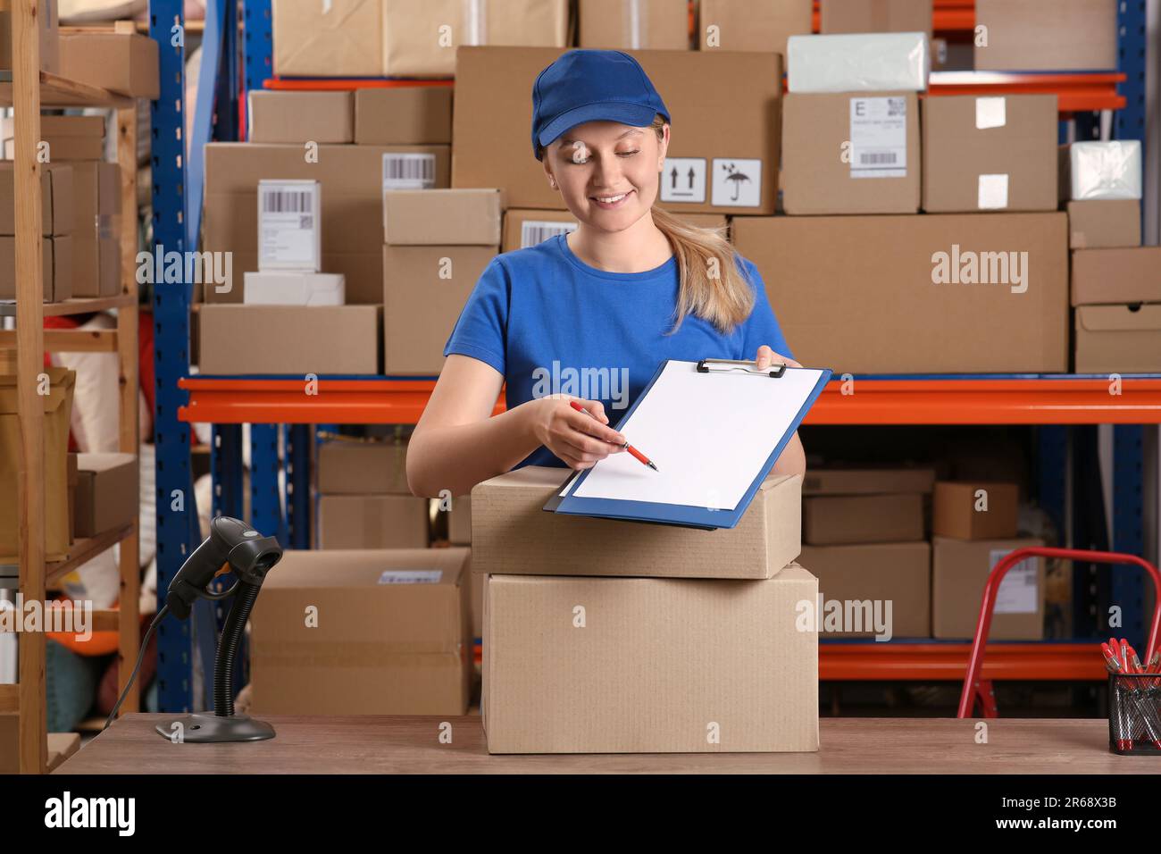 Post office worker with clipboard and parcels near rack indoors Stock ...
