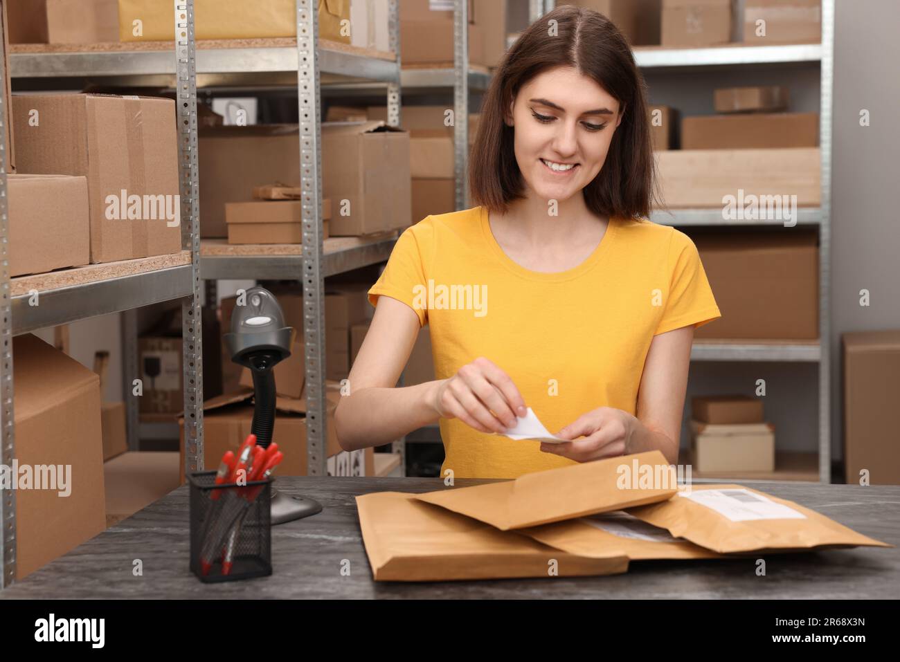Post office worker sticking barcode on parcel at counter indoors Stock ...