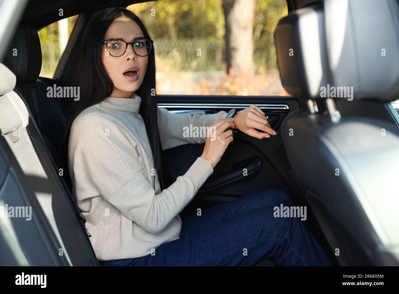 Emotional woman checking time on watch in car. Being late concept Stock ...