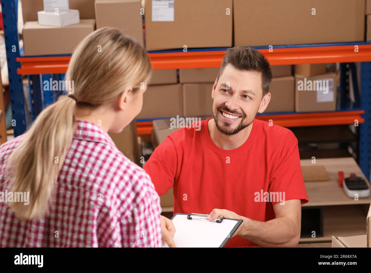 Woman signing papers for delivered parcel at post office Stock Photo ...