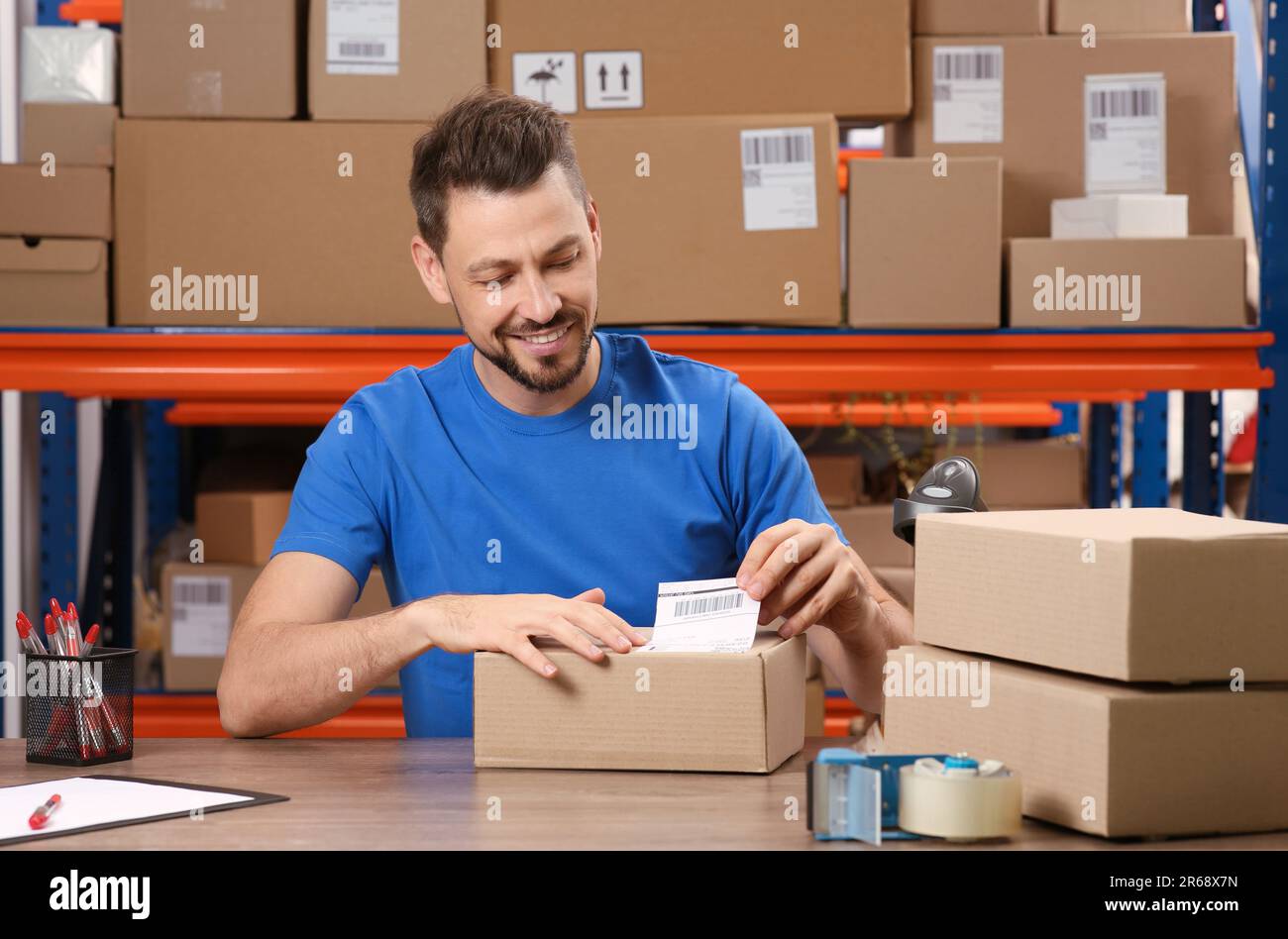 Post office worker sticking barcode on parcel at counter indoors Stock ...