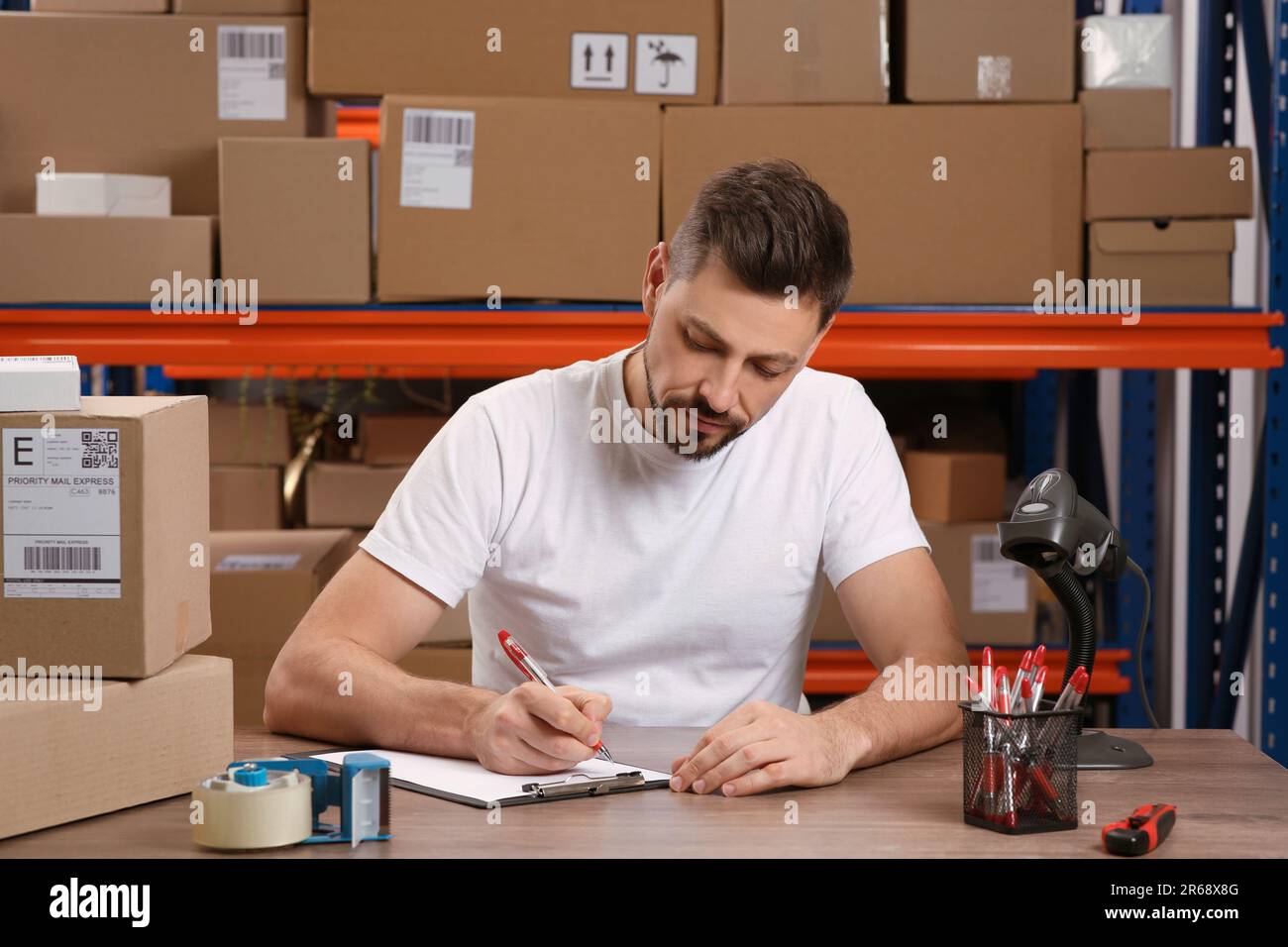 Post office worker with clipboard and parcels at counter indoors Stock ...