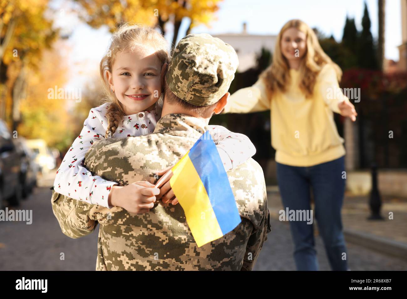 Daughter hugging her father in military uniform and holding Ukrainian ...