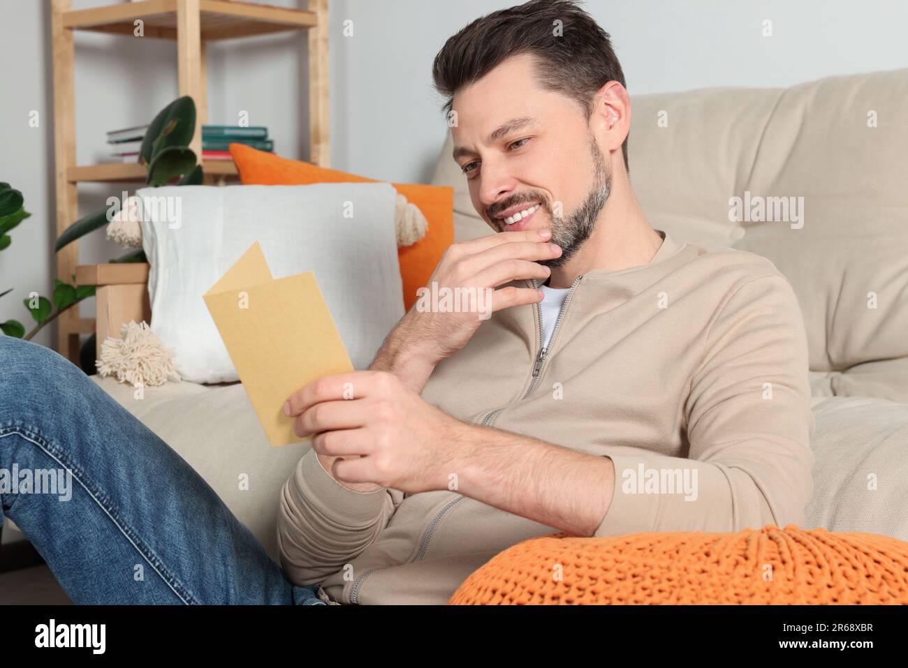 Happy man reading greeting card on sofa in living room Stock Photo - Alamy
