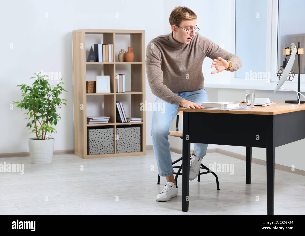 Emotional young man checking time in office. Being late Stock Photo - Alamy
