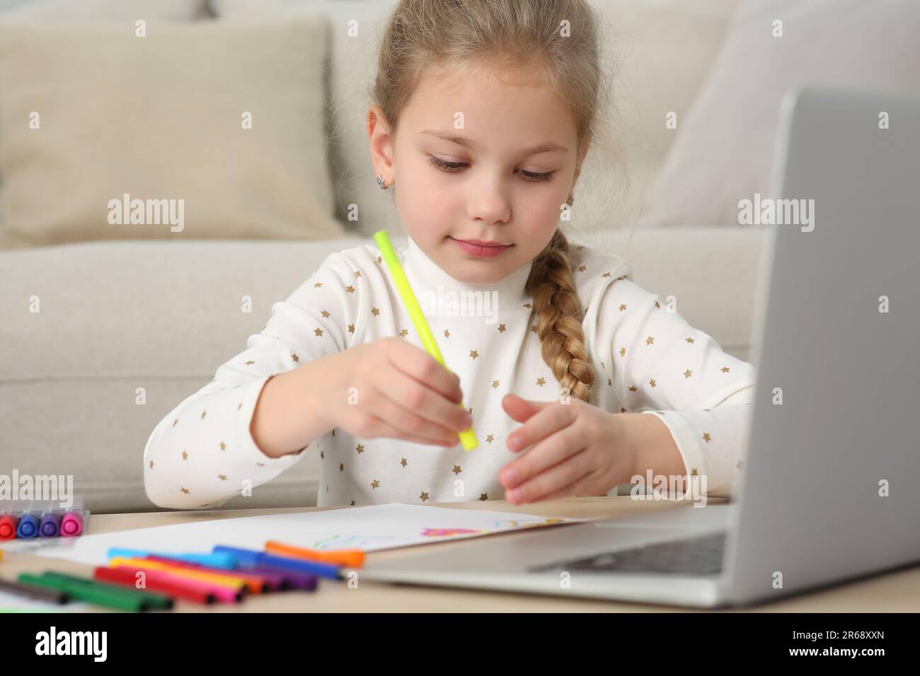 Little girl drawing with felt-tip pen following online course at home ...