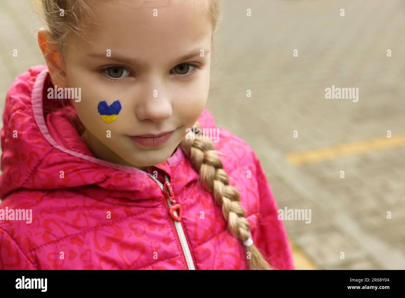 Little girl with drawing of Ukrainian flag on face in heart shape ...