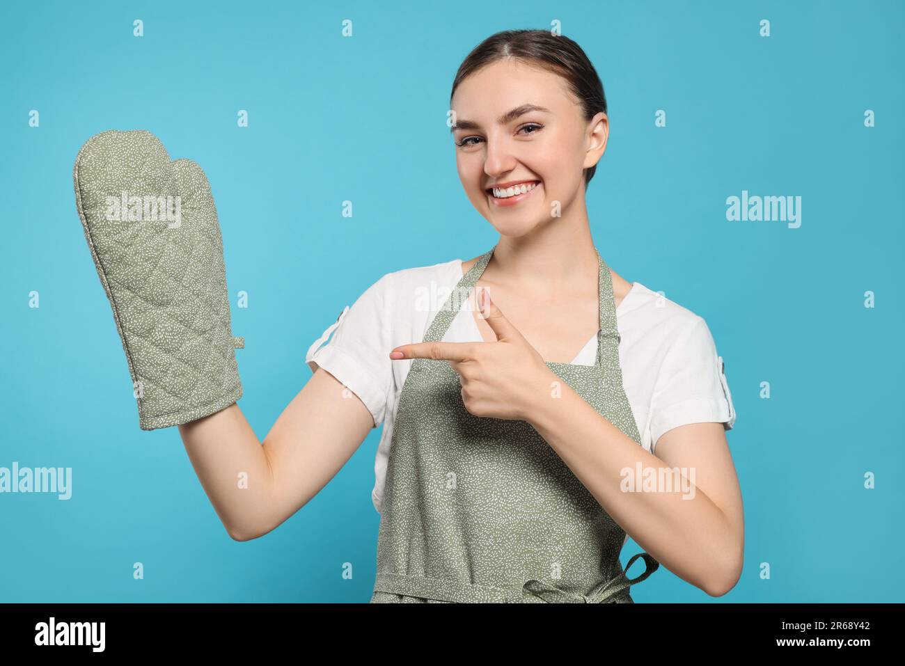 Beautiful young woman in clean apron with pattern and oven glove on ...
