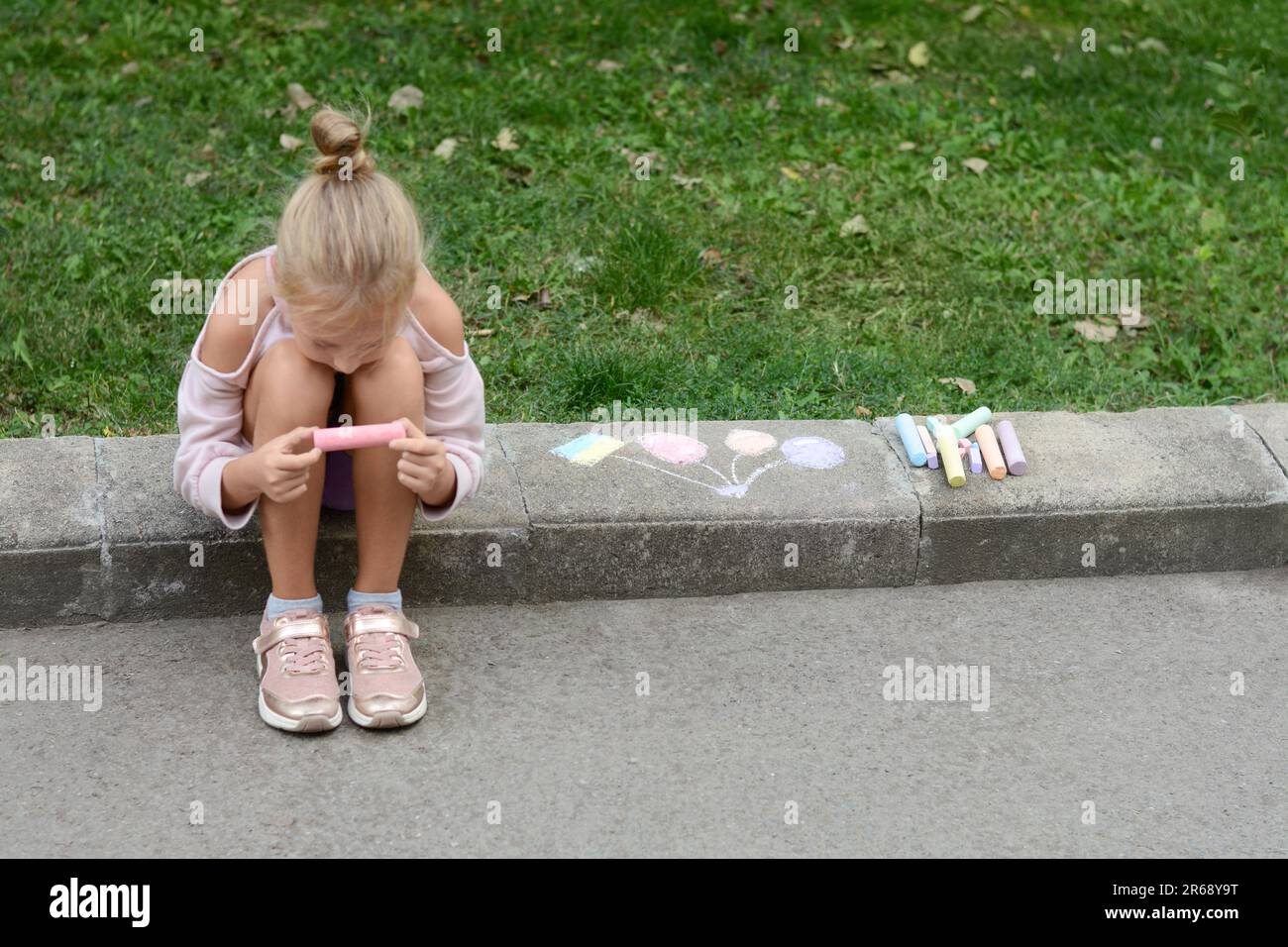 Little child chalk piece sitting on curb outdoors, space for text Stock Photo - Alamy
