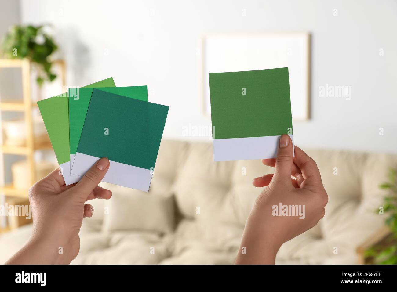 Woman with color sample cards choosing paint shade for wall in room ...