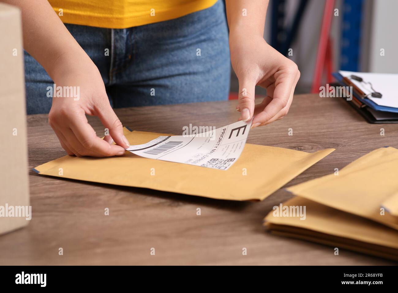 Post office worker sticking barcode on parcel at counter indoors ...