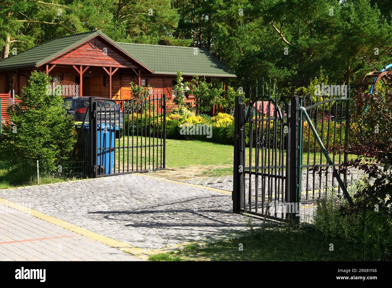 Open metal gates near house, trees and bushes outdoors Stock Photo - Alamy