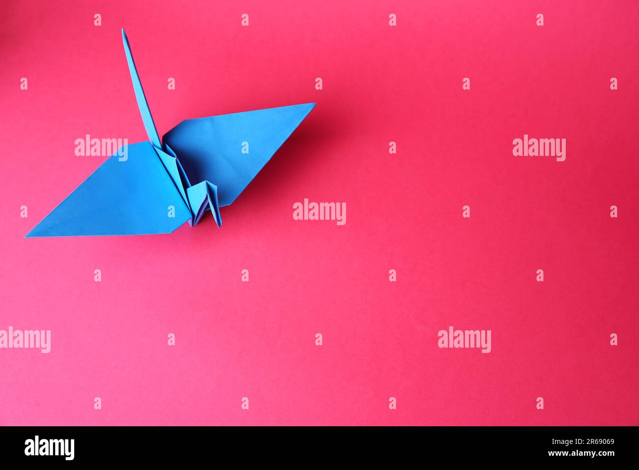 Origami art. Handmade paper crane on pink background, above view. Space ...