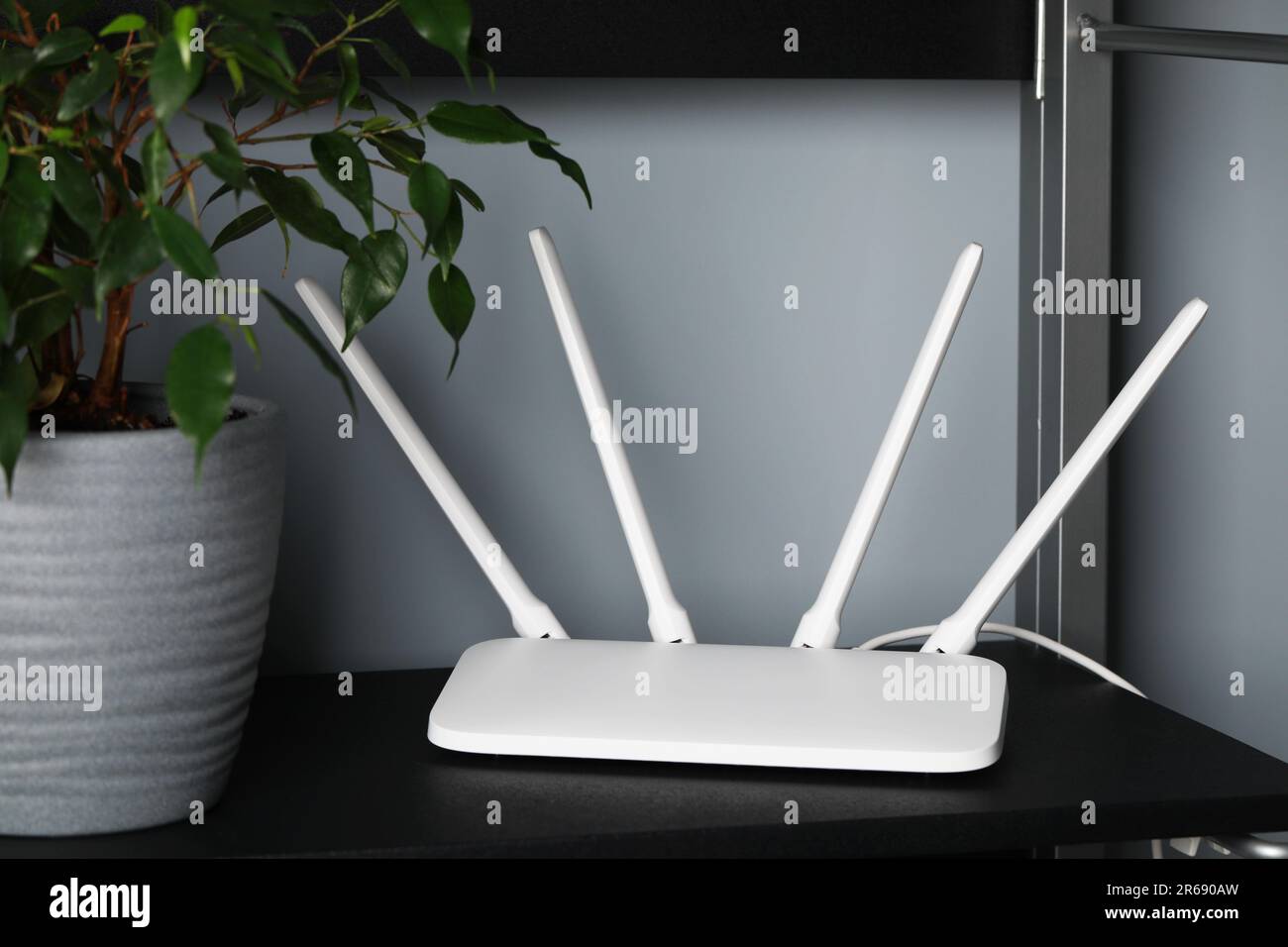 New white Wi-Fi router near potted plant on black shelf Stock Photo - Alamy